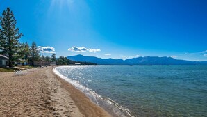 Uma praia com águas cristalinas, areal dourado e montanhas ao fundo.