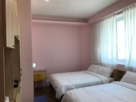 Quarto com duas camas, uma escrivaninha, uma cadeira e um guarda-roupa.