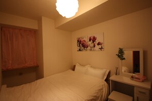 Um quarto com cama, mesa de cabeceira, espelho e um quadro na parede.