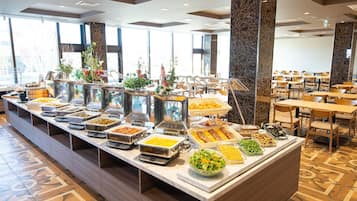 Uma mesa de buffet com diversos alimentos e uma área de refeições com mesas e cadeiras.