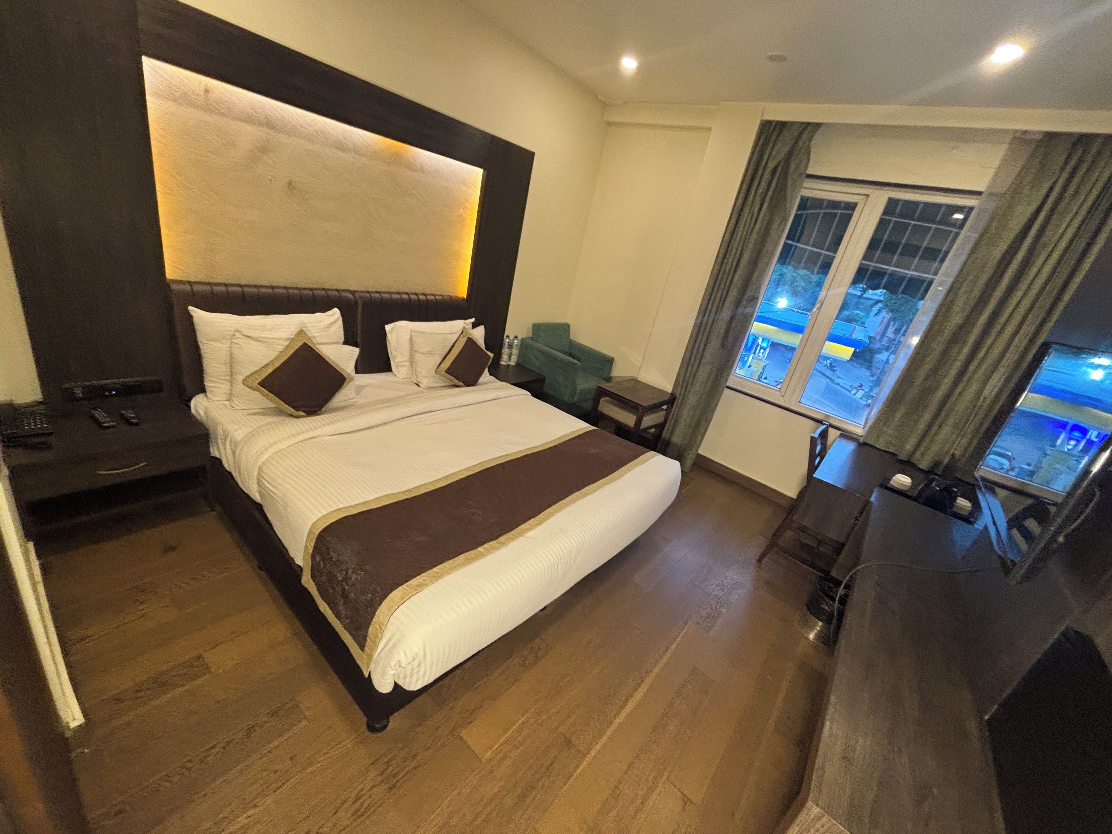 Quarto de hotel com uma cama grande, mesas de cabeceira, escrivaninha e vista para a cidade.