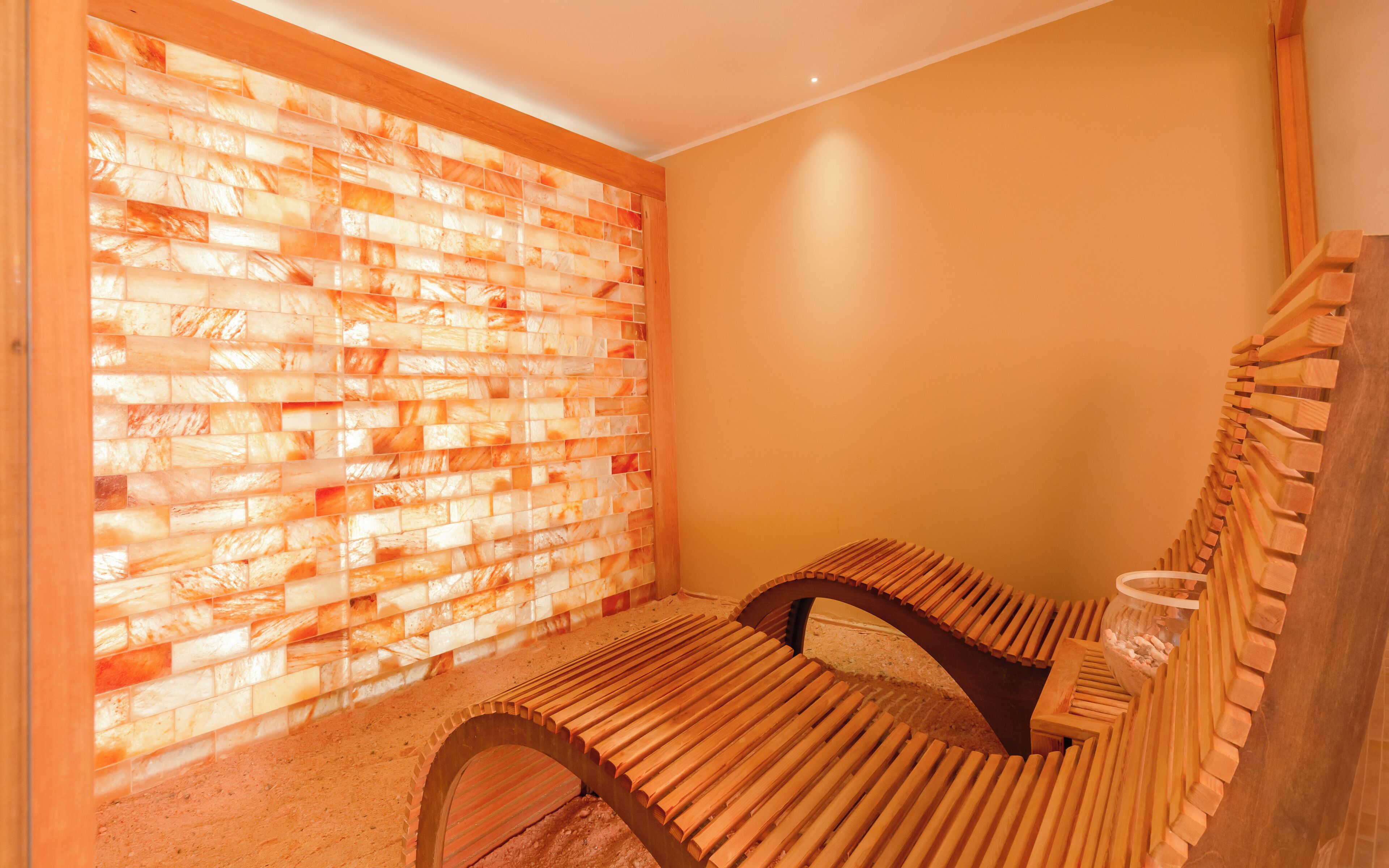 Uma sala de sauna com bancos de madeira e parede em mosaico.
