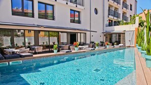 Um hotel moderno com piscina, área de estar ao ar livre e vista para os edifícios ao redor.