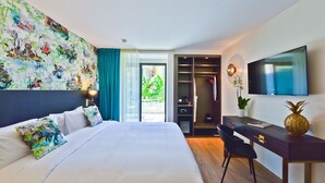 Quarto de hotel com uma cama grande, uma escrivaninha com televisão, um guarda-roupa e vista para o exterior.