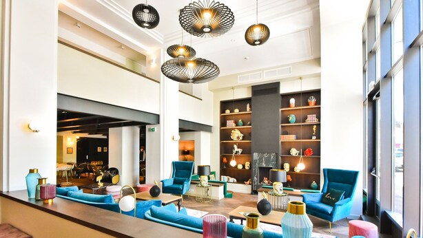Um lobby de hotel moderno com assentos azuis, vasos decorativos e uma lareira.