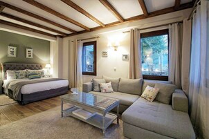 Quarto com cama, sofá, mesa de centro de vidro e janela com cortinas.