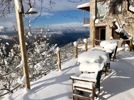 Área de estar ao ar livre coberta de neve com vista para montanhas.
