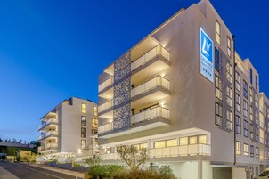 Um hotel com vários andares, varandas, uma placa indicando que é um hotel 4 estrelas e um design arquitetônico moderno.