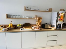 Uma bancada de cozinha com diversos itens de café da manhã, uma torradeira, uma cafeteira e uma seleção de frutas.