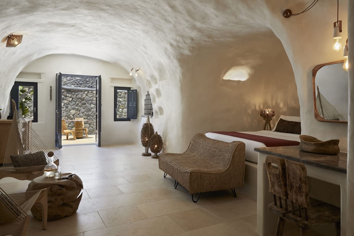 Um interior acolhedor e moderno, com uma parede de pedra, um sofá de vime, uma mesa de jantar de madeira e um espelho grande.