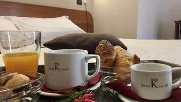 Disposição para o pequeno-almoço com croissants, um copo de sumo de laranja e duas chávenas com o logótipo do hotel.