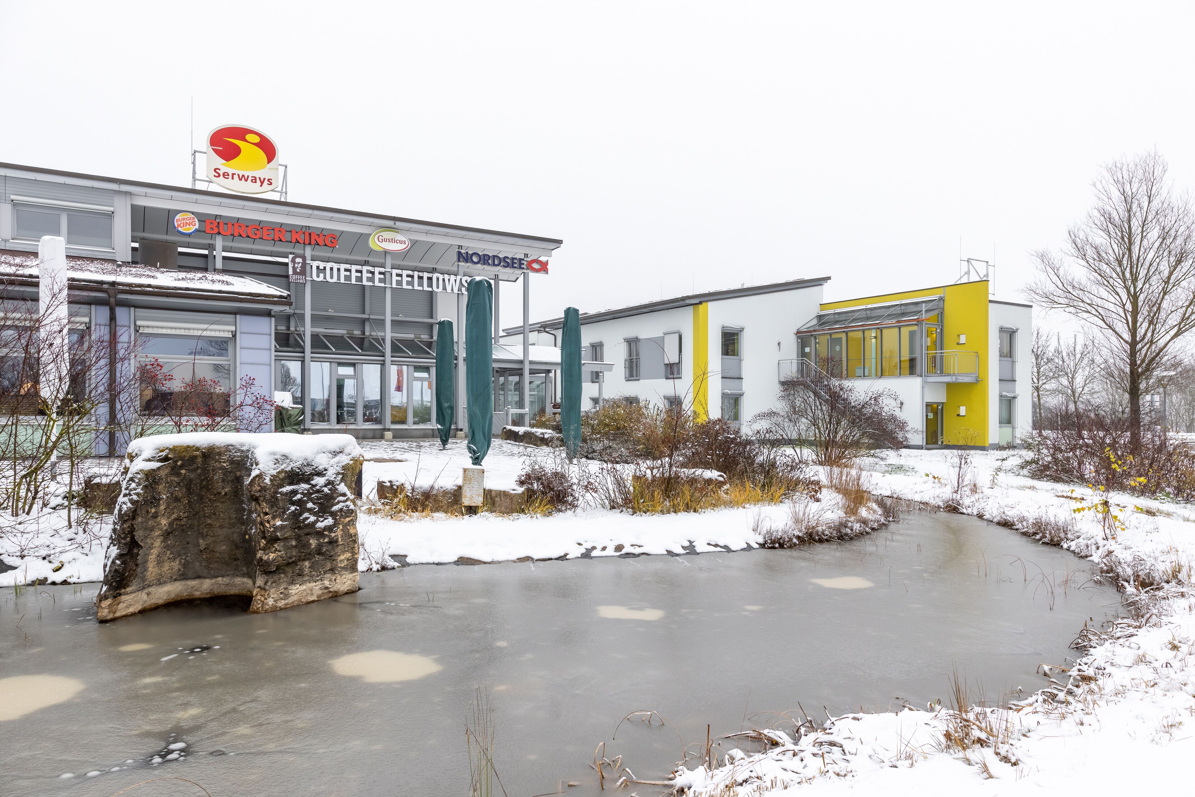 Um edifício comercial com Burger King, Nordsee e uma cafeteria.