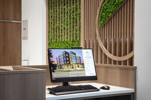 Monitor de computador exibindo um site de hotel, teclado e rato sobre uma mesa.