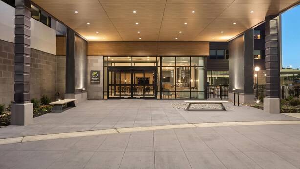 Uma entrada de edifício moderna com porta de vidro, um banco e um caminho de ladrilhos.