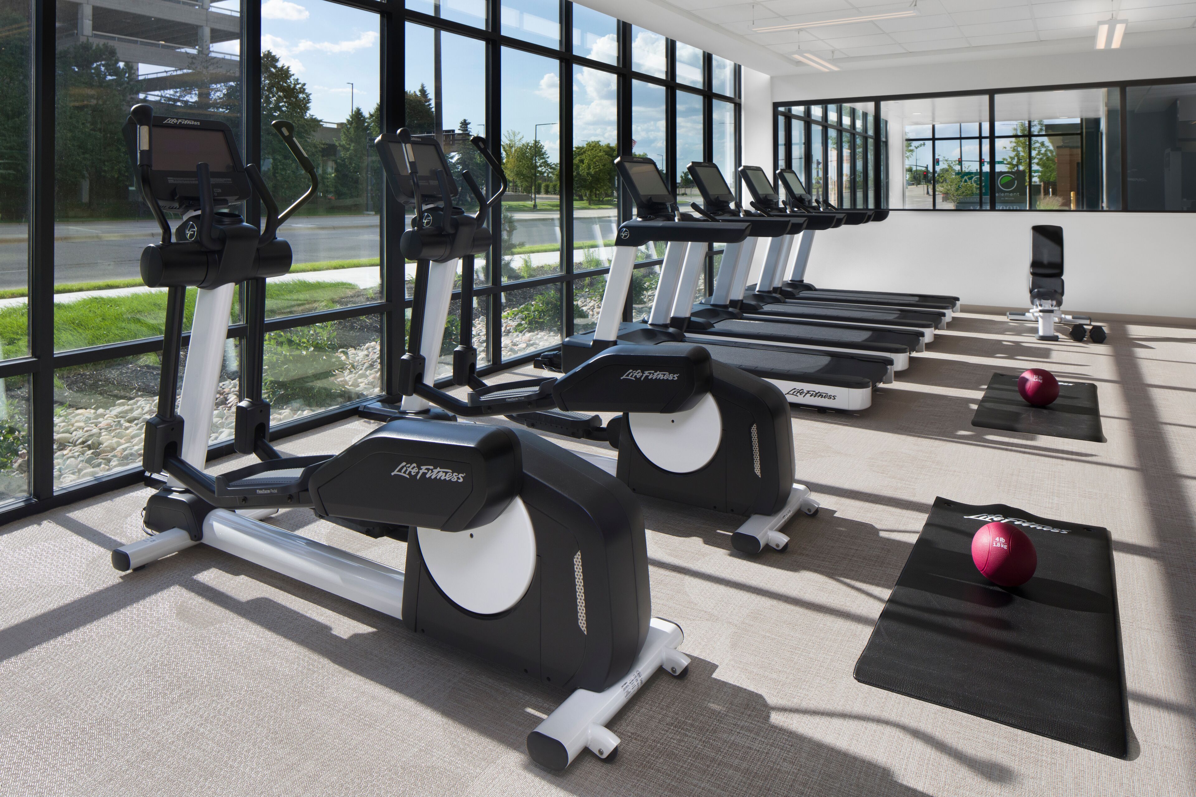Uma academia com esteiras, elípticos e bolas de exercício.