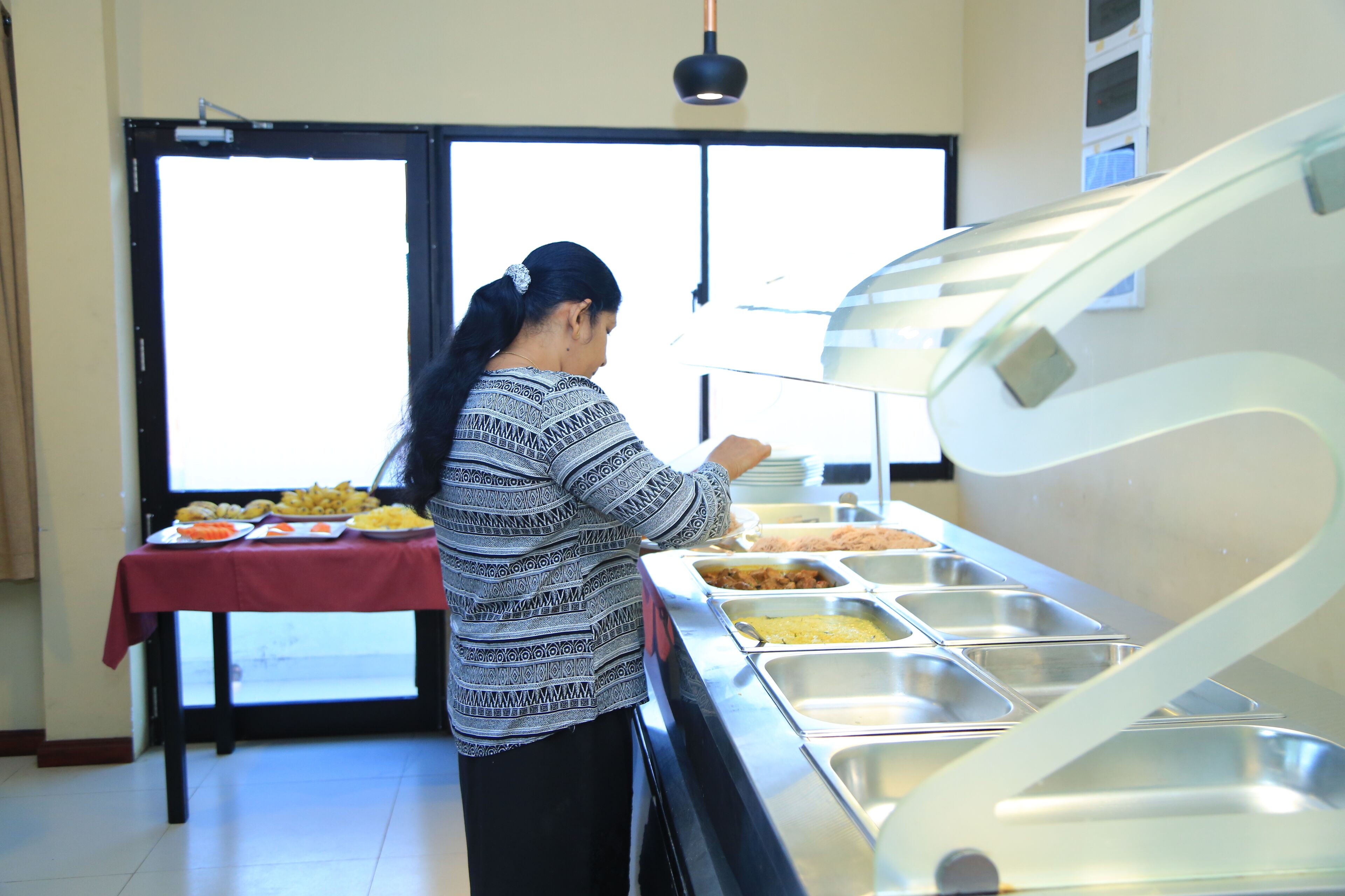 Disposição de buffet com diversos alimentos e uma pessoa servindo.
