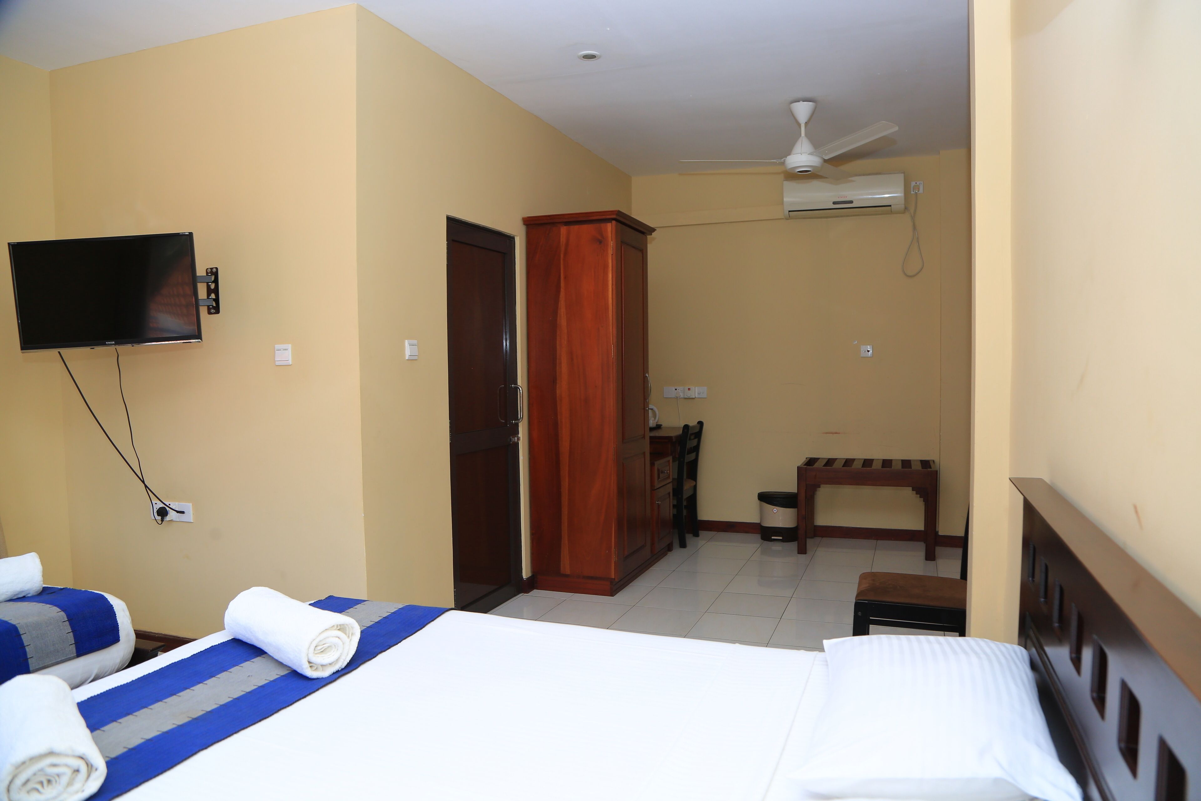 Quarto de hotel com uma cama, televisão na parede, guarda-roupa, secretária e uma cadeira.