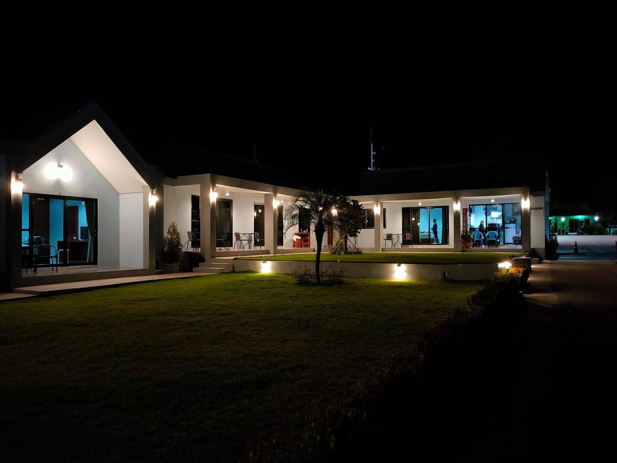 Uma casa moderna de dois andares com um alpendre coberto, gramado e uma pequena árvore.