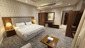 Quarto de hotel com cama, mesas de cabeceira, escrivaninha e área de estar.