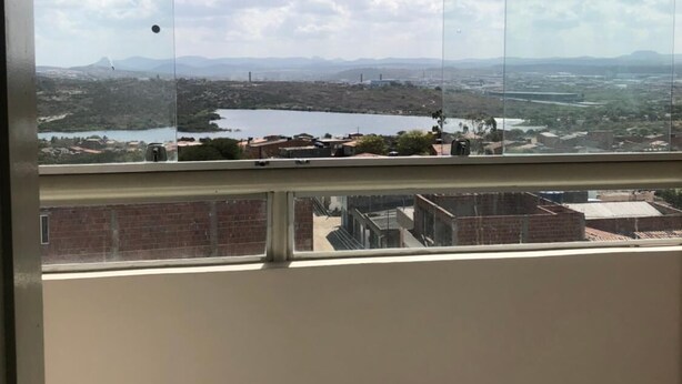 Quarto com uma grande janela com vista para um lago e montanhas ao longe.
