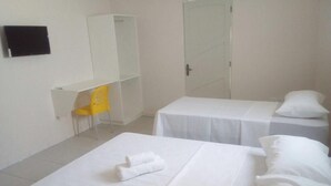 Quarto de hotel com duas camas de solteiro, uma cadeira, uma escrivaninha e uma porta.