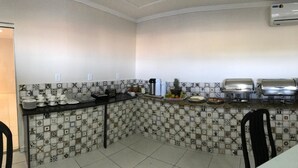 Uma cozinha com painel de azulejos, bancada com diversos utensílios e fogão embutido.
