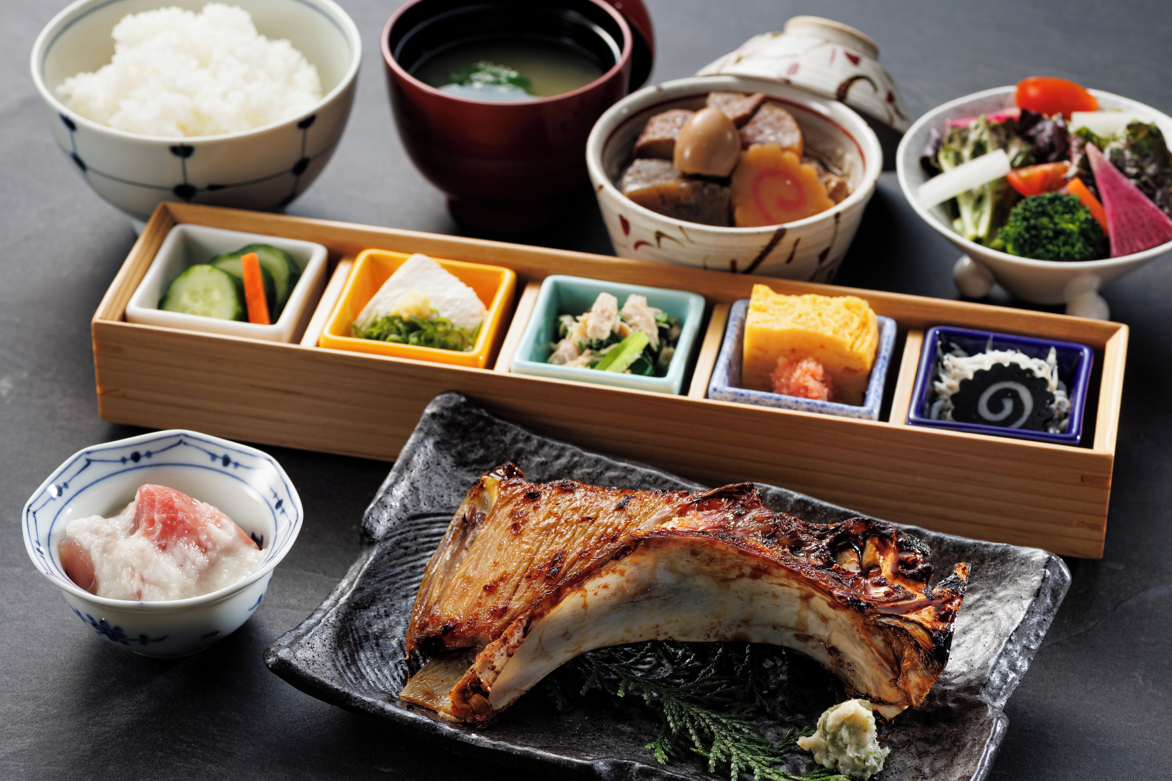 Uma refeição tradicional japonesa com diversos pratos, incluindo arroz, sopa e sashimi.