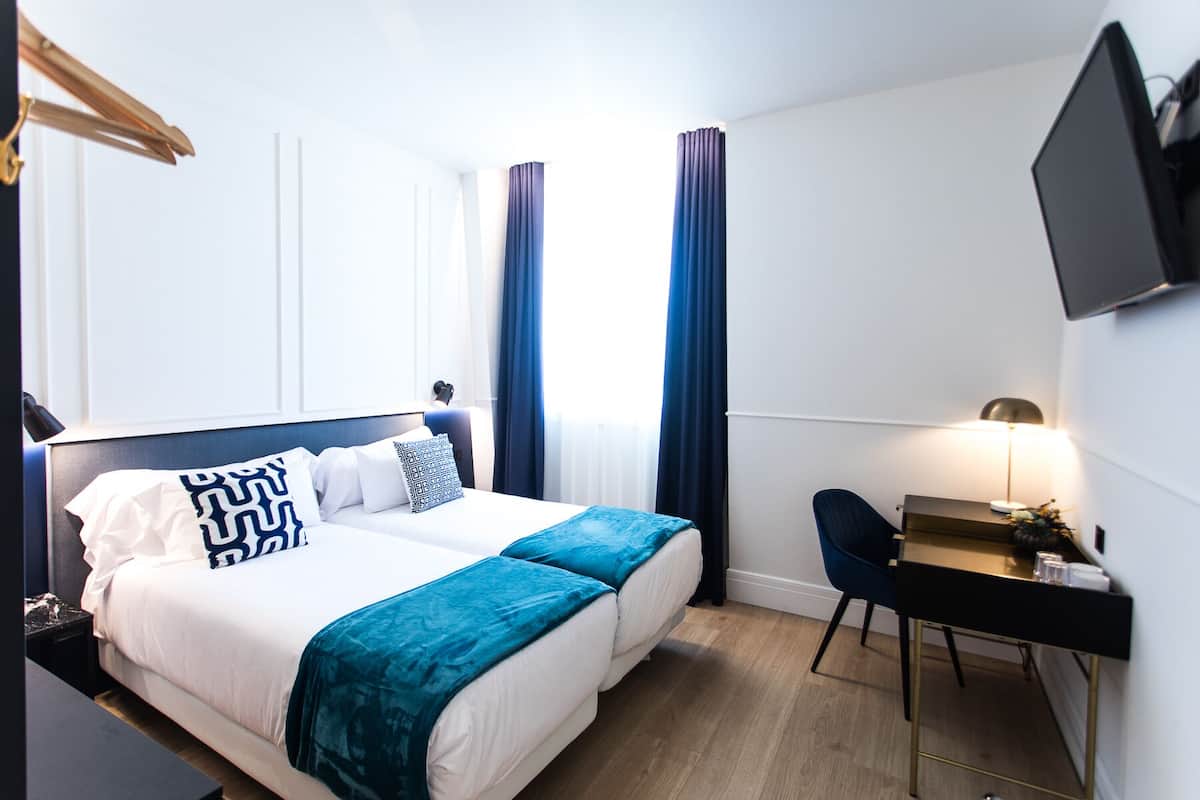Quarto de hotel com cama, escrivaninha e televisão.