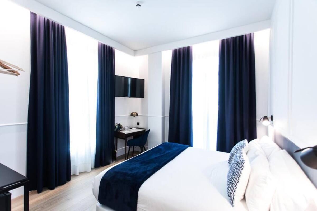 Quarto de hotel moderno com uma cama, uma escrivaninha e uma cadeira.