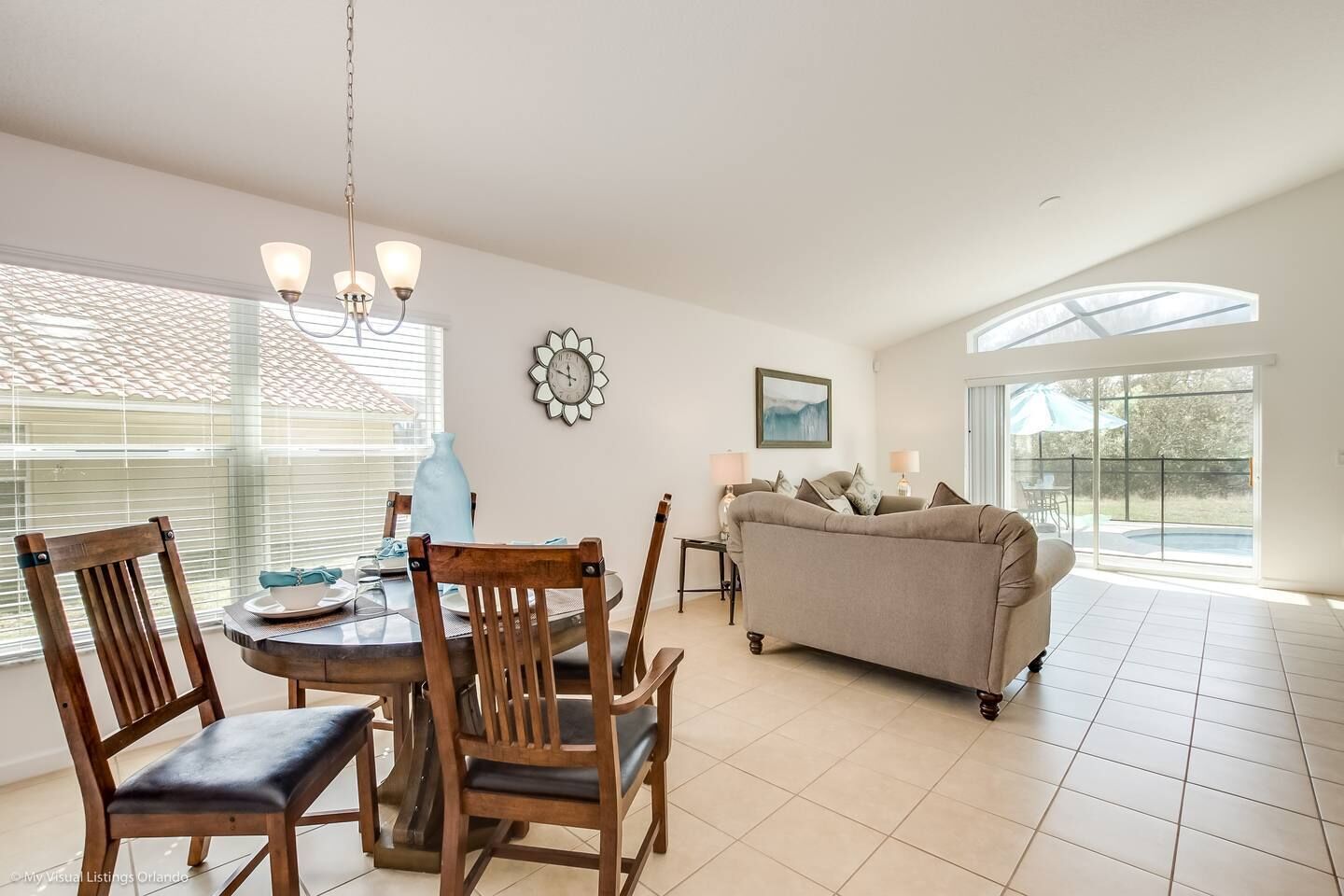 Uma sala ampla com uma mesa de jantar, cadeiras, um sofá e uma grande janela com vista para o exterior.