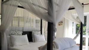 Uma cama de dossel com roupa de cama branca e vista para o exterior.