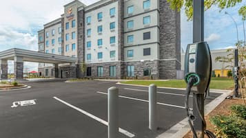 Hotel com design moderno, com estacionamento e pontos de carregamento para veículos elétricos.
