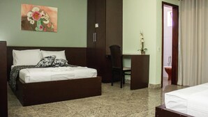 Quarto com cama, escrivaninha, guarda-roupa e um quadro na parede.