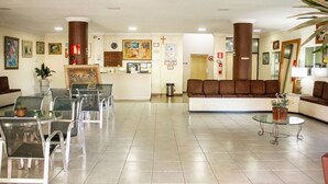 Um hall amplo com balcão de recepção, área de estar e um espelho grande.