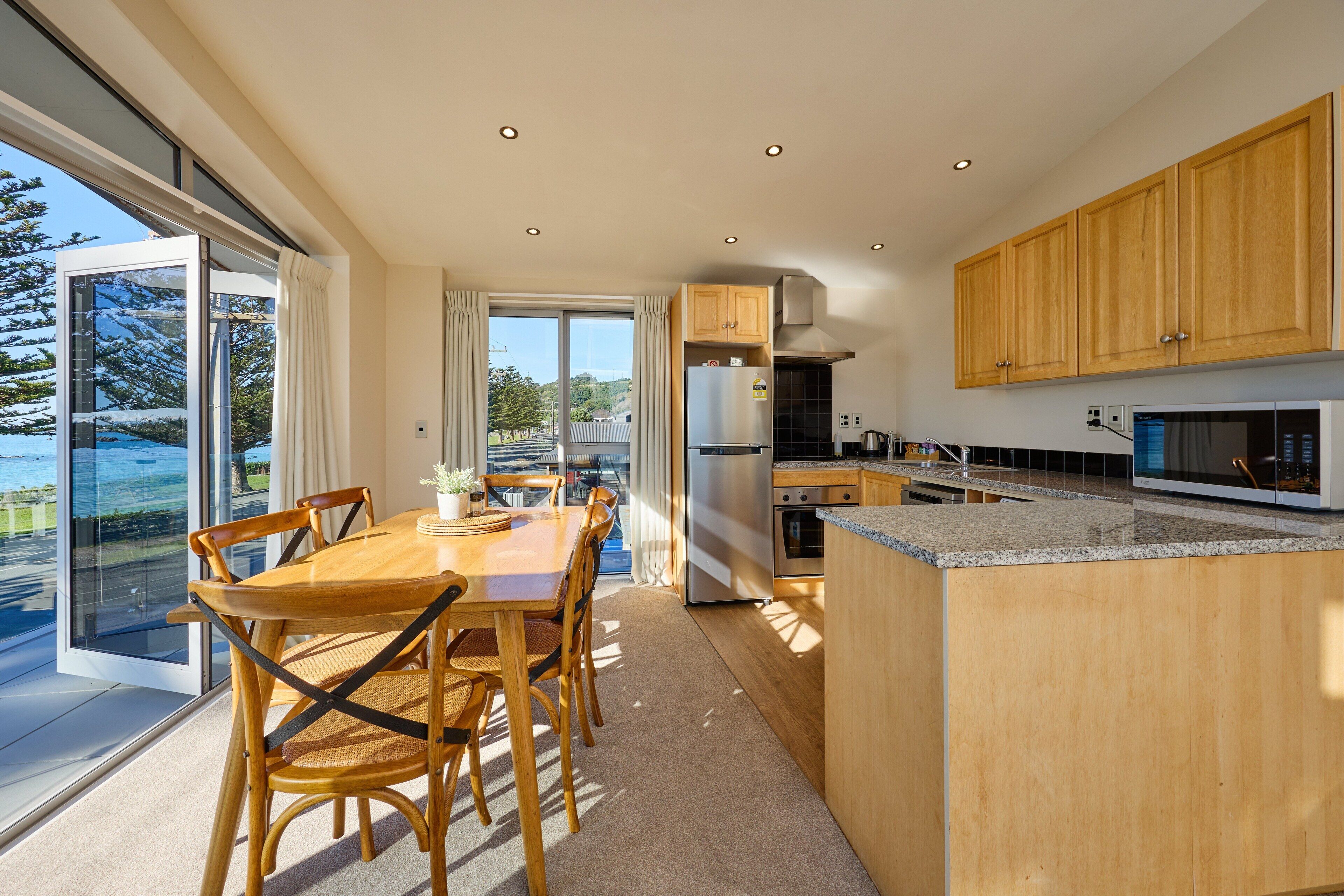 Uma cozinha moderna com armários de madeira, uma ilha central e uma área de refeições com vista.