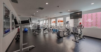 Uma academia com diversos equipamentos de exercícios, incluindo esteiras e aparelhos de musculação.