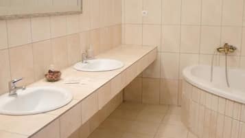 Casa de banho com duas pias, um espelho e uma banheira.