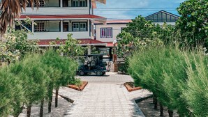 Um edifício de dois andares com telhado vermelho e um caminho de paralelepípedos que leva a um carrinho de golfe.