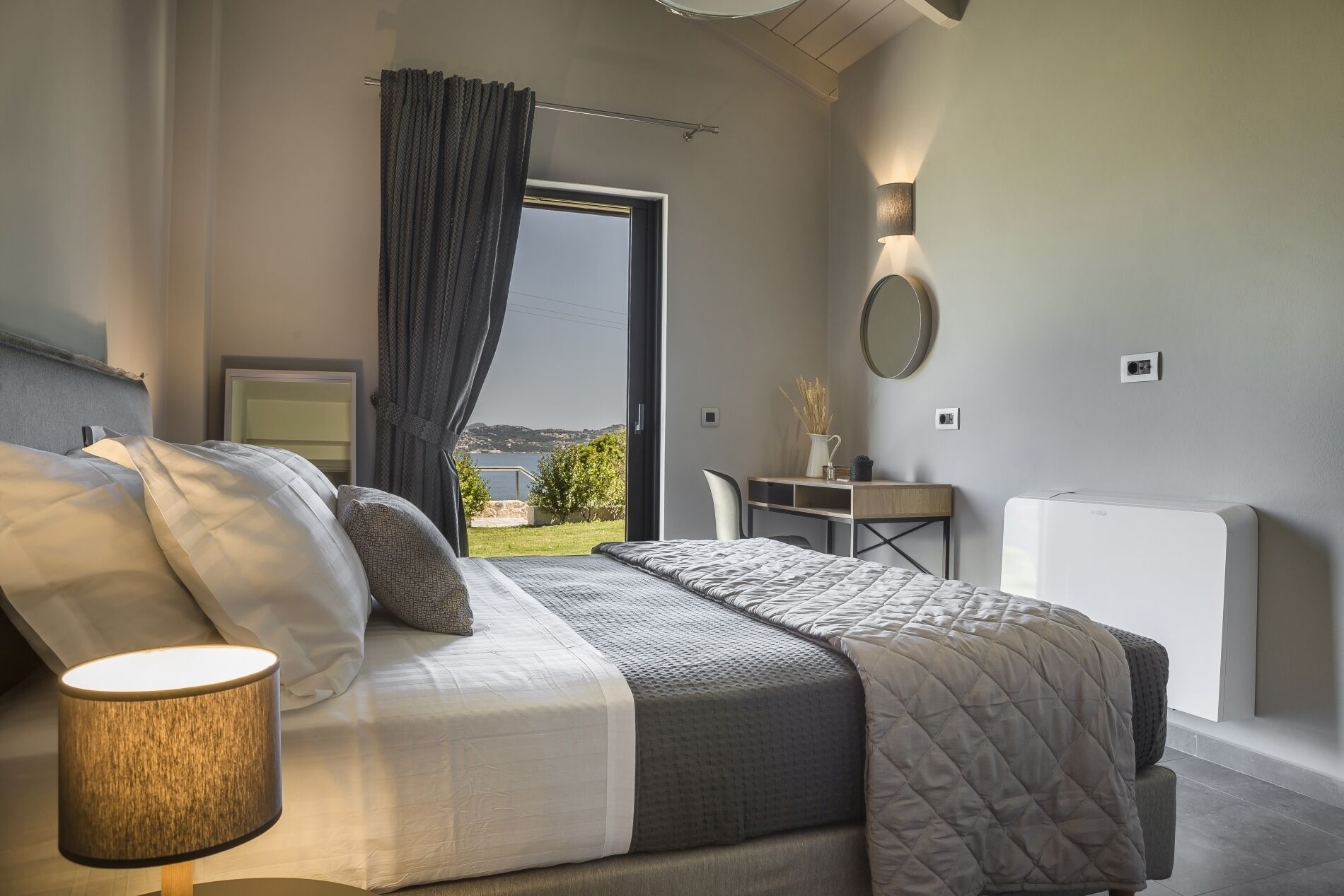 Quarto com cama, escrivaninha e vista para o exterior.
