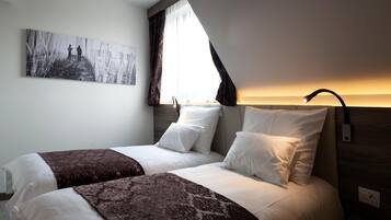 Quarto de hotel com duas camas, uma janela grande com cortinas, um quadro na parede e uma mesa de cabeceira com abajur.