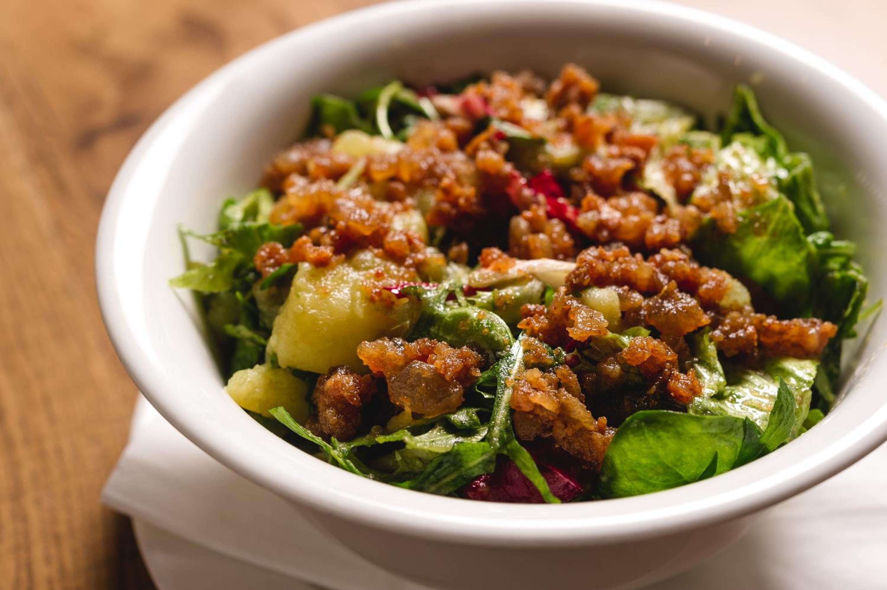 Uma salada com croutons e folhas verdes.