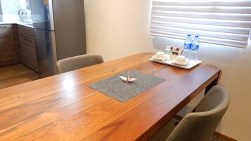 Uma mesa de jantar de madeira com um jogo de sousa e um objeto decorativo, uma garrafa de água e uma xícara em um suporte.