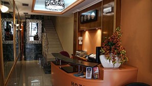 Uma receção de hotel com design moderno, uma escadaria ao fundo e um relógio na parede.