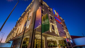 Um hotel com várias bandeiras, incluindo a bandeira da União Europeia, e um letreiro de neon.