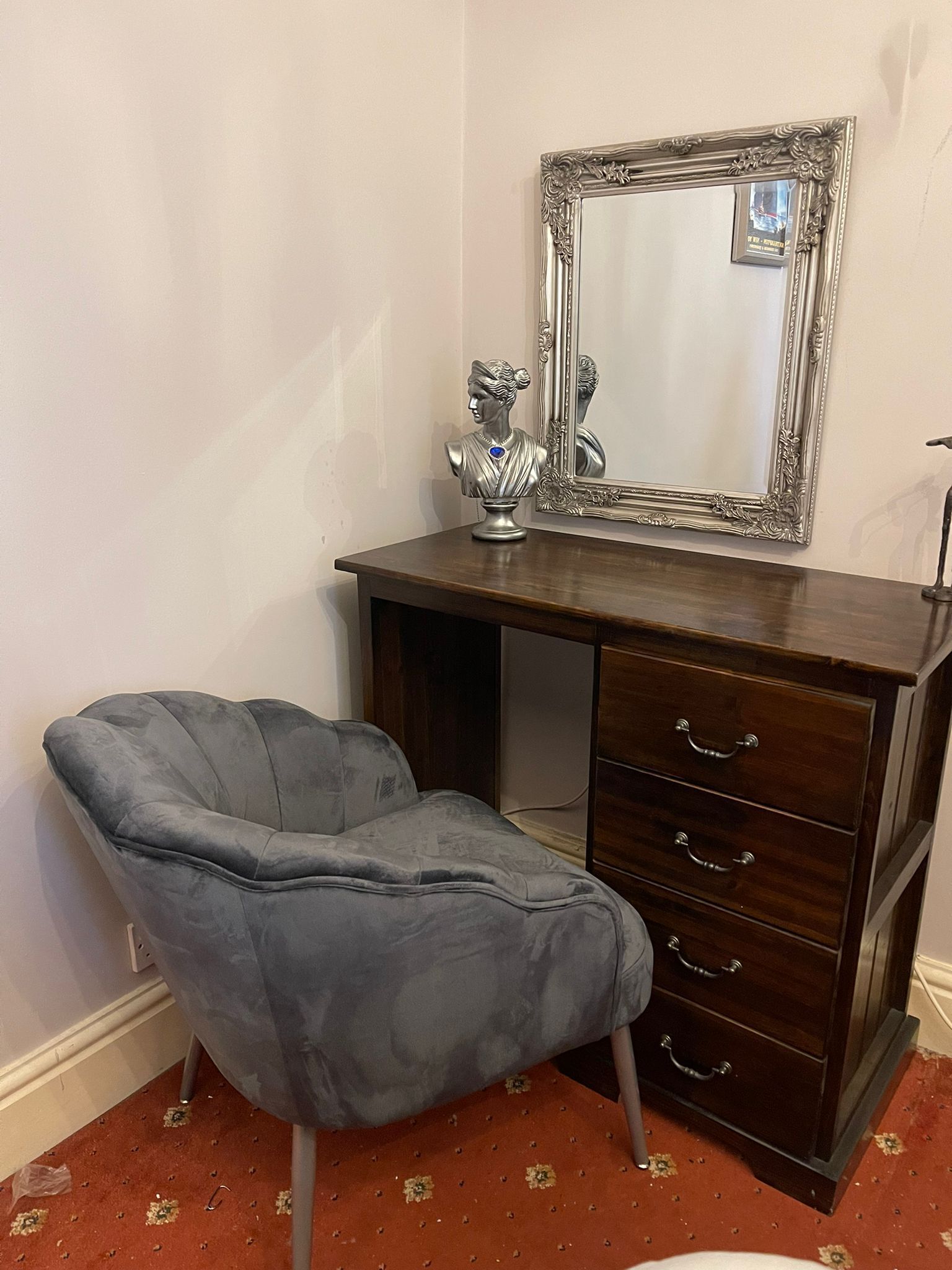 Quarto com cômoda de madeira, espelho e cadeira cinza.