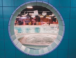 Piscina interna com hidromassagem, rodeada por um painel de azulejos.