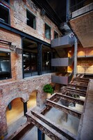 Um interior com vários níveis, paredes de tijolo aparente, uma escada e um mezanino.