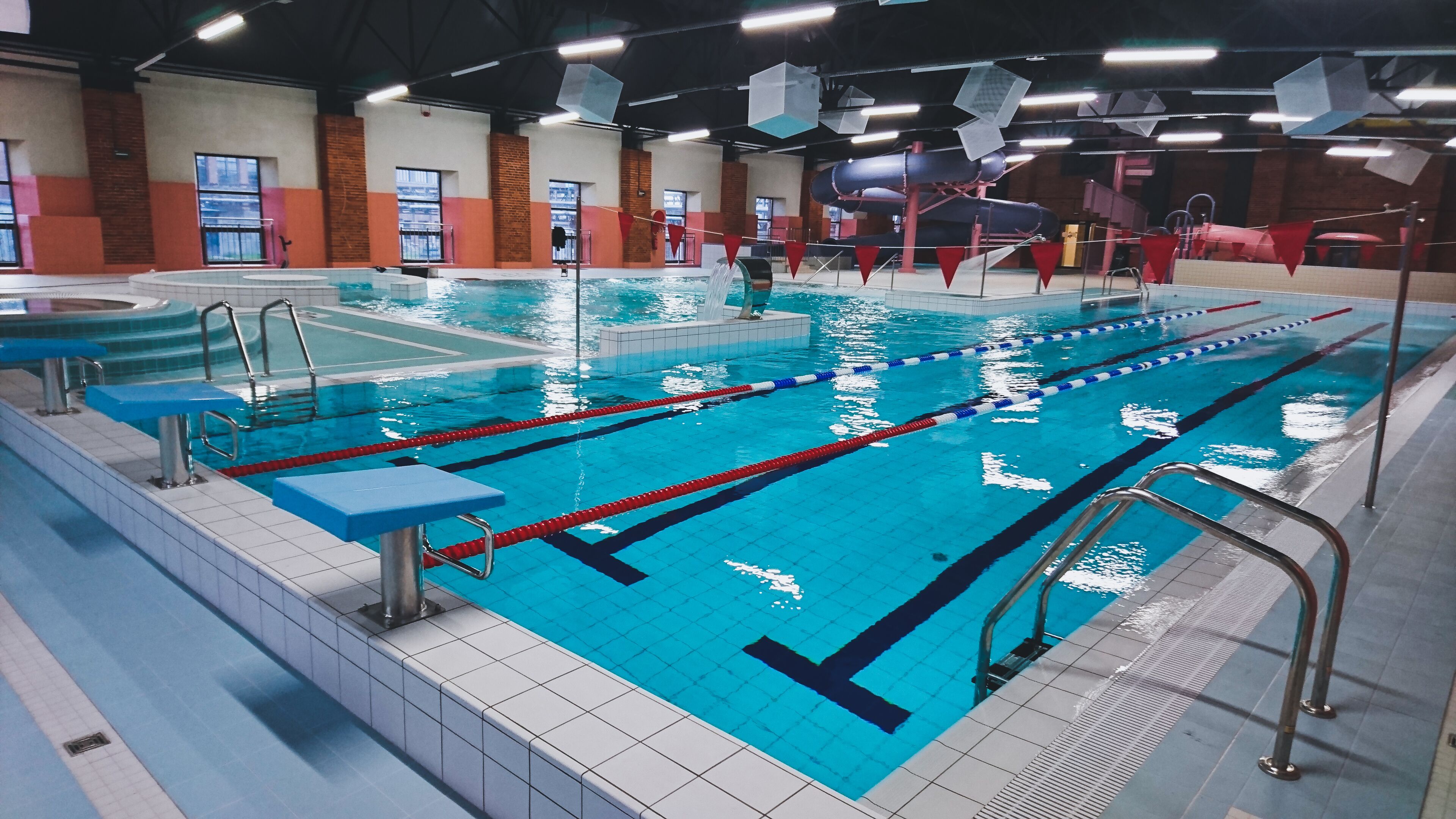 Piscina interior com várias pistas, blocos de partida e guarda-corpos de segurança.