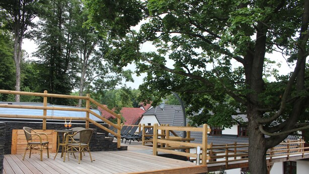 Um deck de madeira com mobiliário externo e uma parede de pedra.