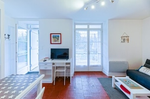 Quarto com escrivaninha, cadeira e sofá. Há janelas e um radiador.